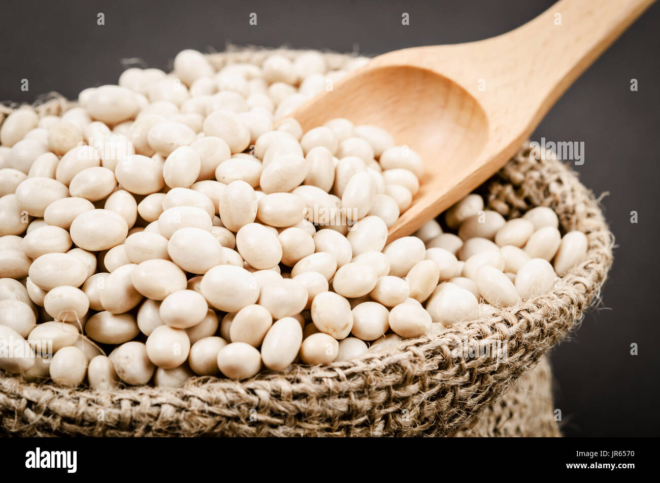 white beans in sack bag with wooden scoop on black background Stock ...