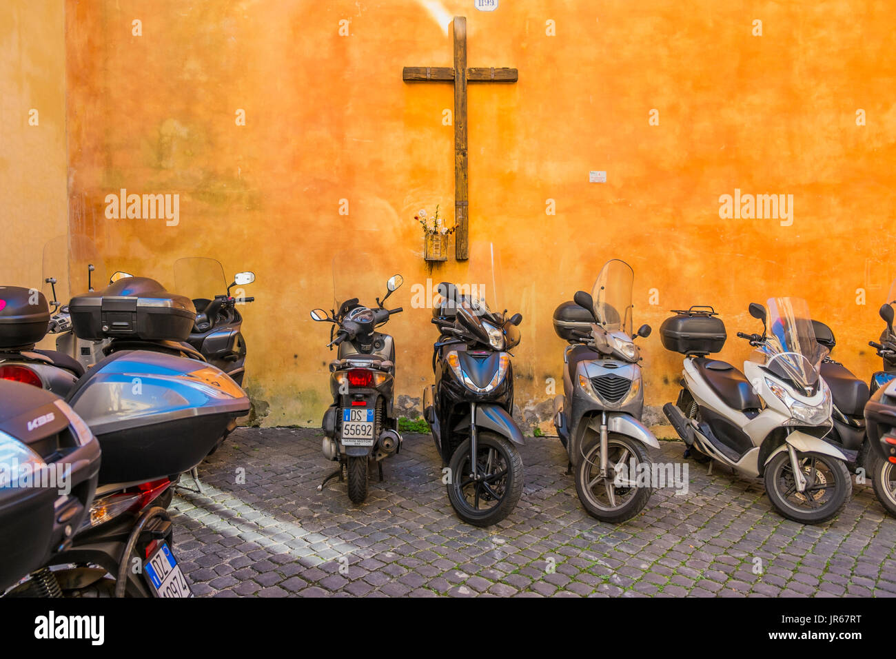 roman scooters, parked in a yard with a cross on the back wall Stock ...