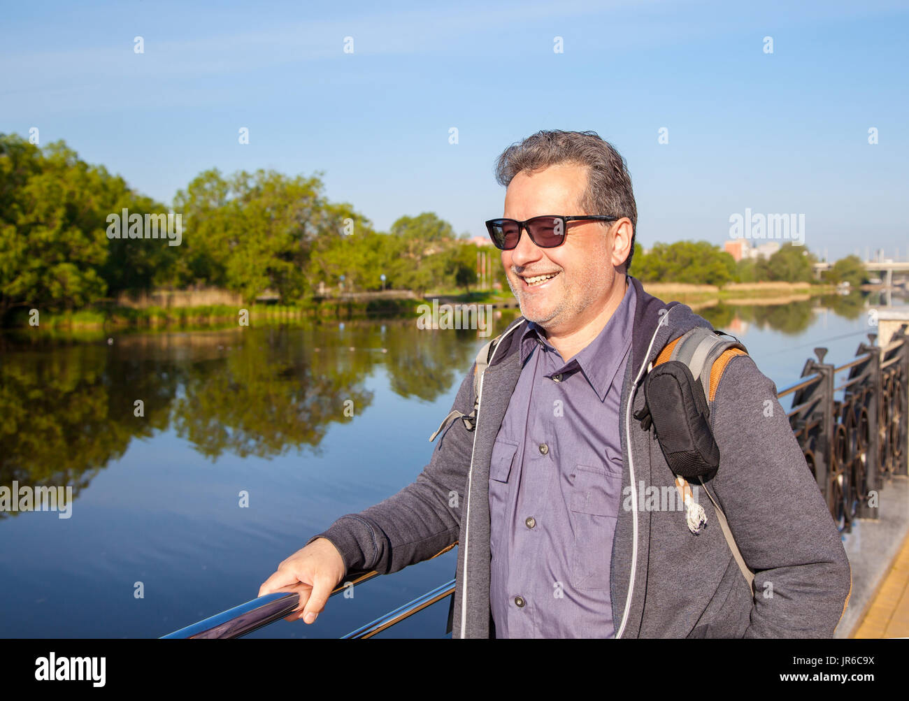 Portrait of a smiling man standing by a river Stock Photo - Alamy