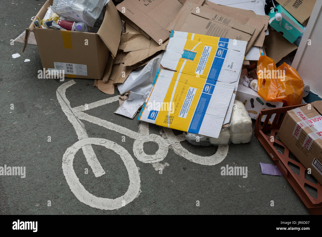 A cycle lane is partially blocked by an overspill of rubbish and litter ...