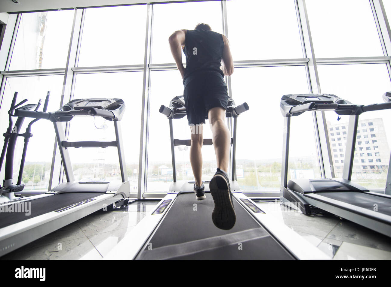 Back view of young man athlete with running on treadmill in gym Stock ...