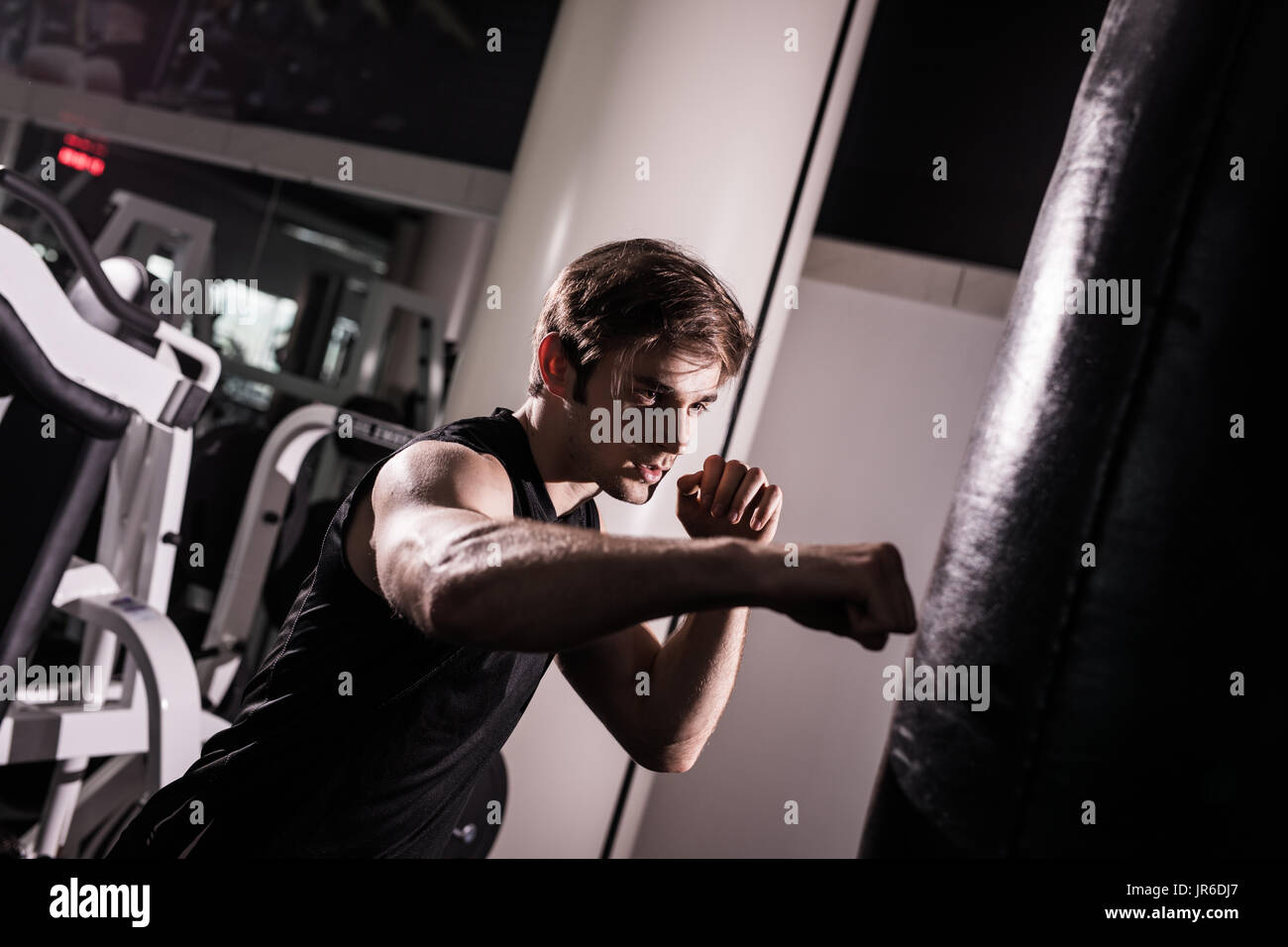 Young athlete working out by throwing punches at a heavy punching bag ...
