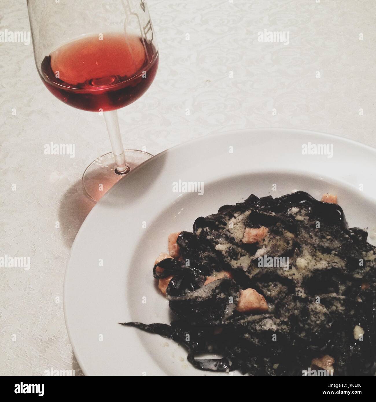 Squid ink pasta with salmon and a glass of red wine Stock Photo - Alamy