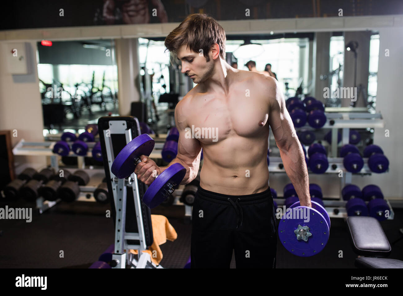very power athletic guy , execute exercise with dumbbells, in gym Stock ...