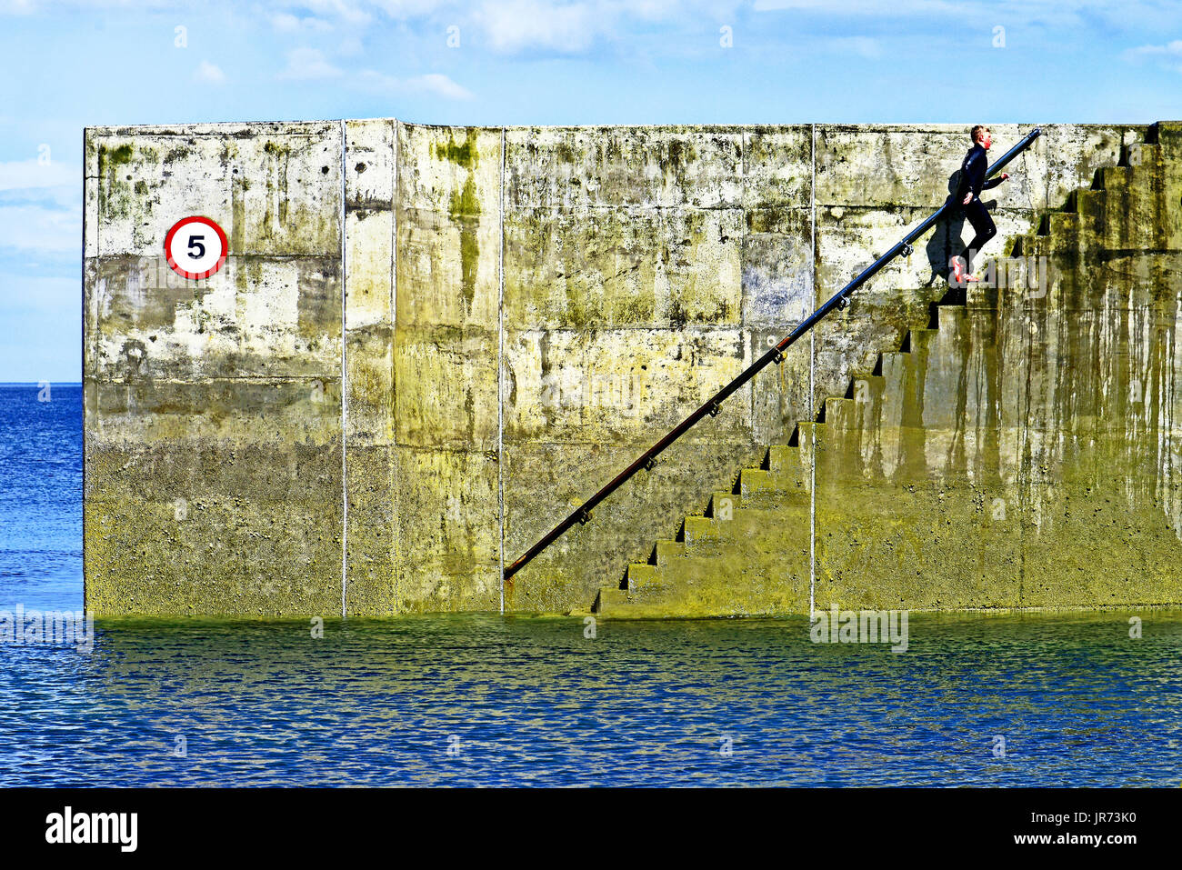 Boy in wet suit running up harbour steps Cullercoats Stock Photo - Alamy