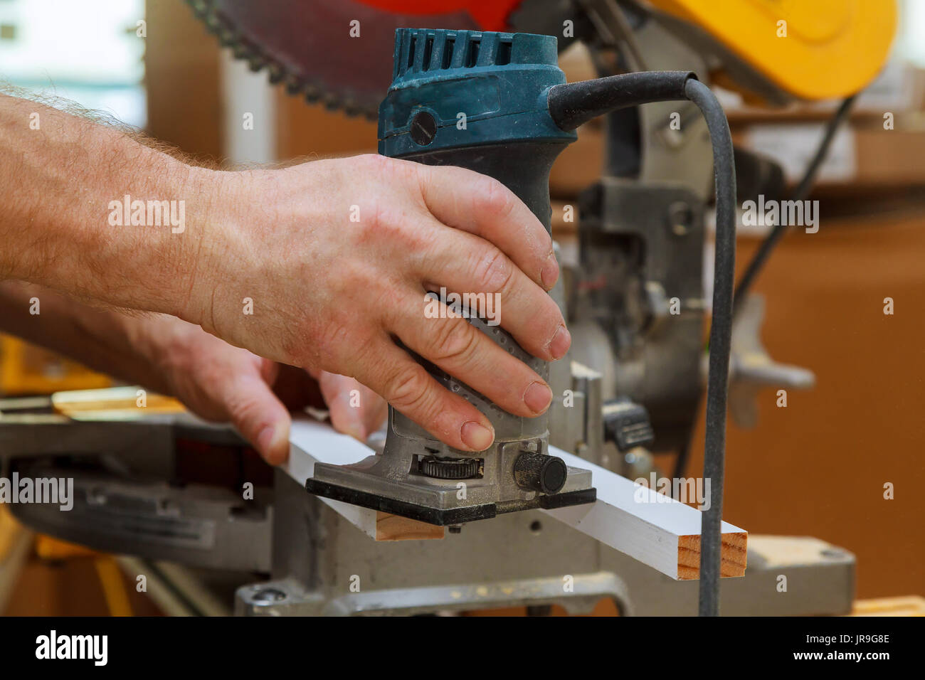 workers using electric routering to cut down stripes on the wood Stock ...
