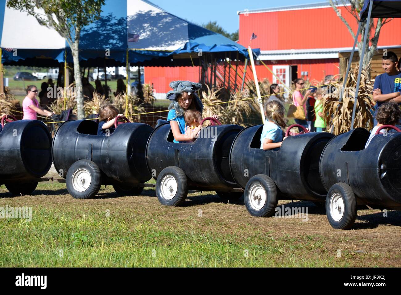 Young girl and female toddler (sisters) riding a barrel train at a fall ...