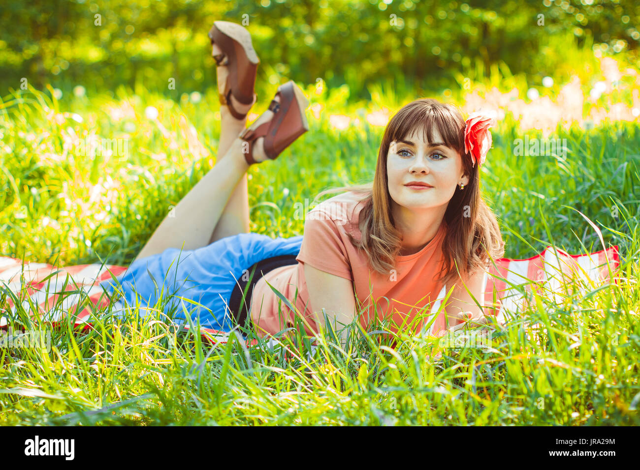Beautiful smiling woman lying on a grass outdoor. She is absolutely ...