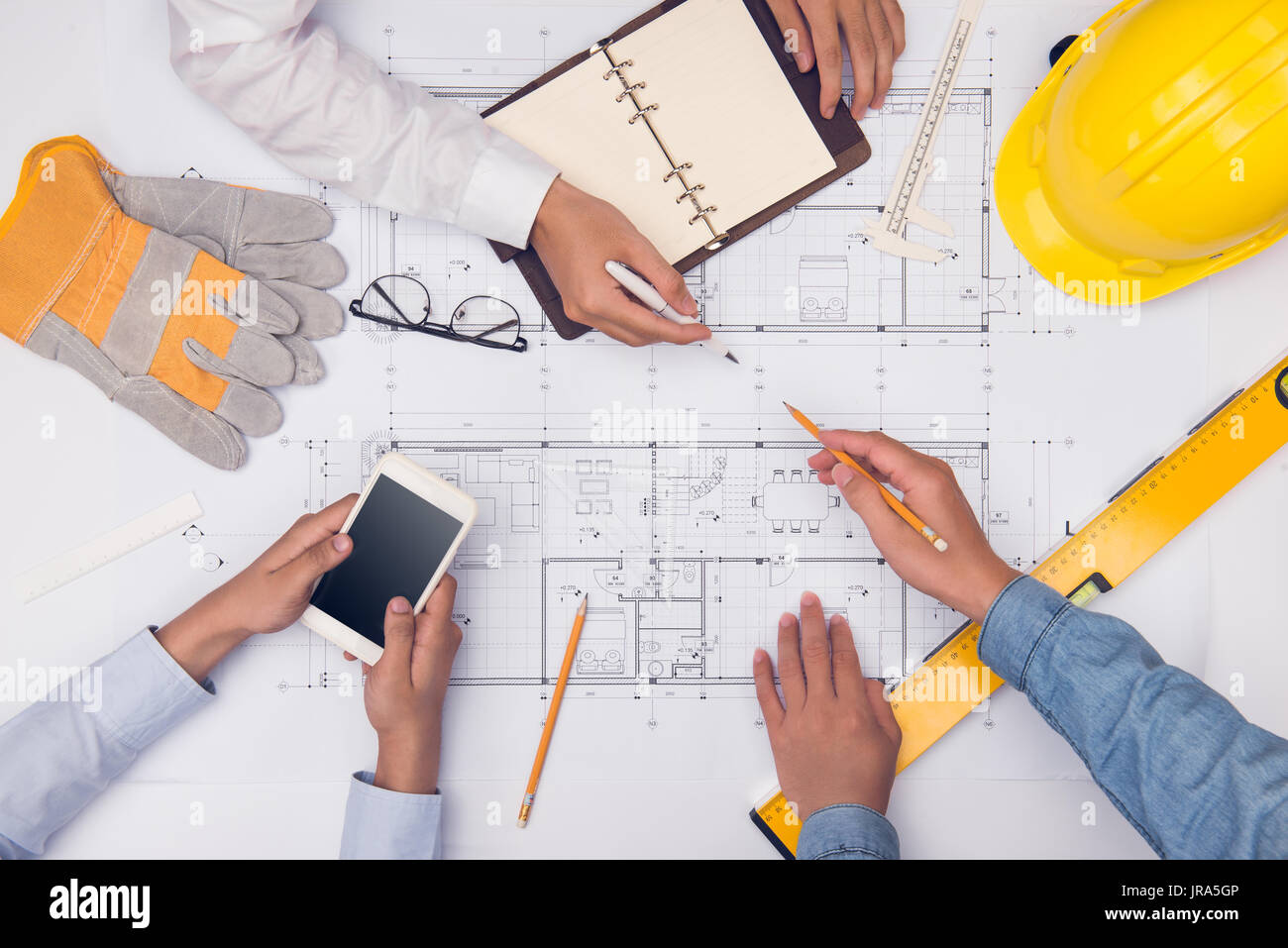 Hands of professional architects discussing and working with blueprints ...