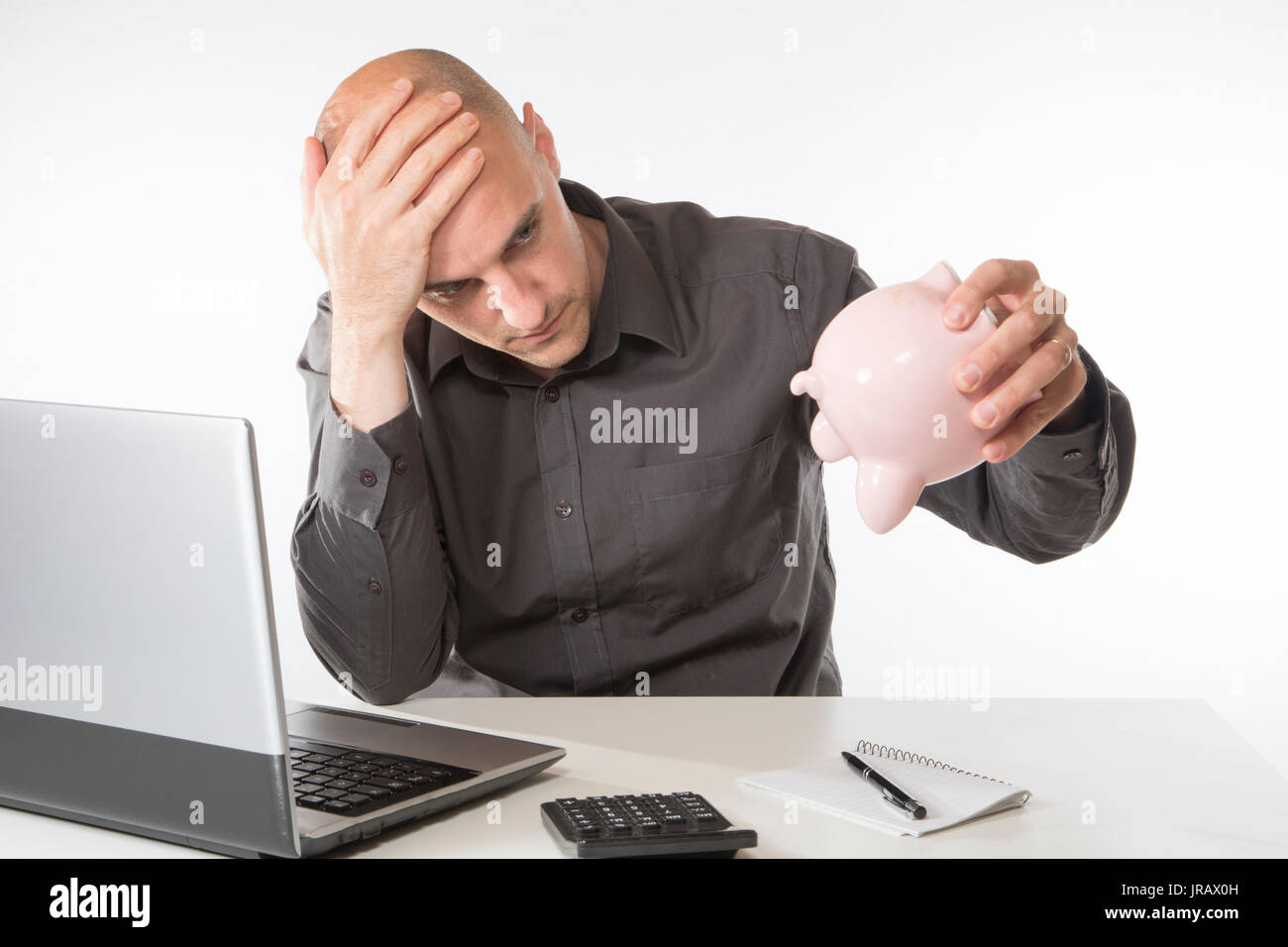Desperate man holding his piggy bank upside down and shaking it in the ...
