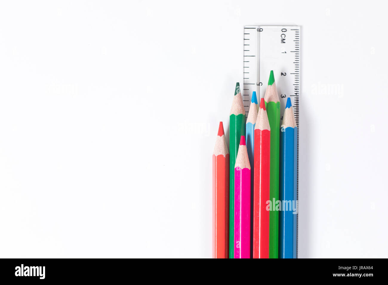 Set of colored pencil crayons with a ruler over a white background with ...