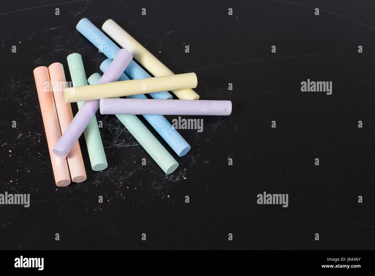 Assorted colored chalks on a chalkboard or slate background with copy ...