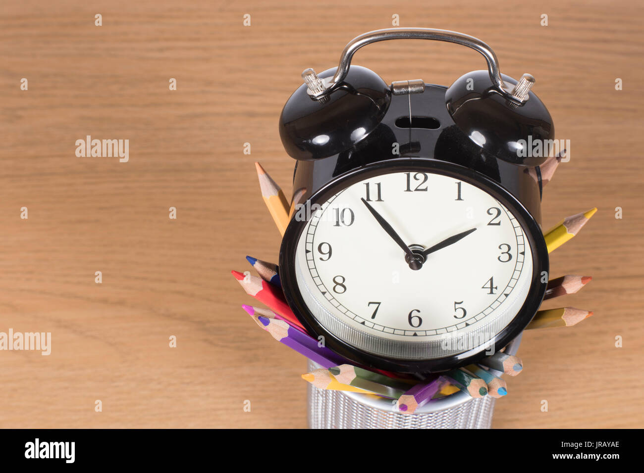 High angle view of alarm clock put in container with colored pencils ...