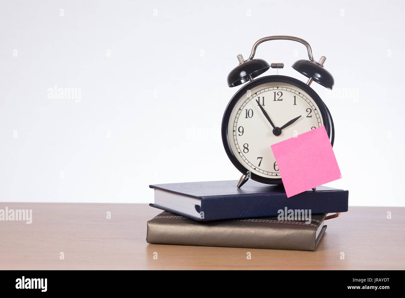 Alarm clock with sticky note standing on pile of calendars on desk ...