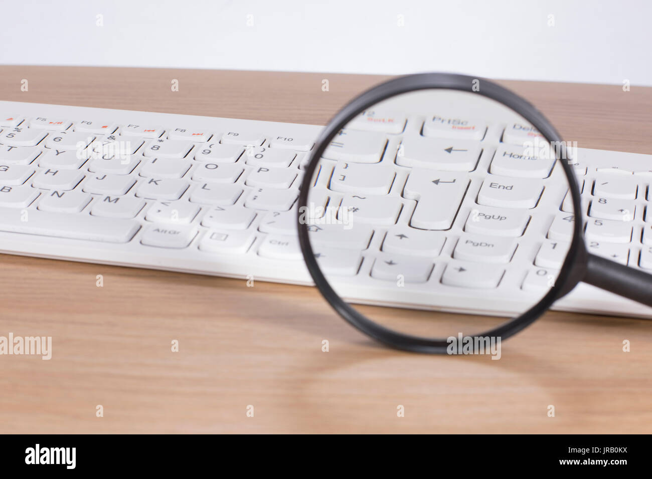 Computer keyboard enlarged through a magnifying glass in a conceptual ...