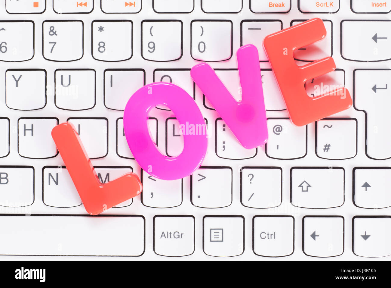 The word love of colorful red and pink toy letters over white computer ...