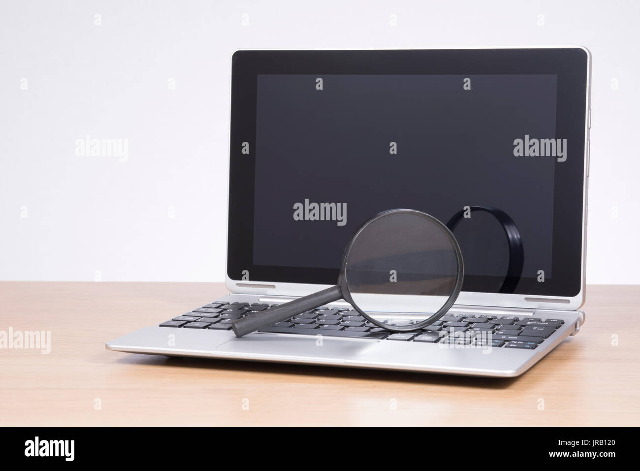Magnifying glass on keyboard of open laptop computer Stock Photo - Alamy