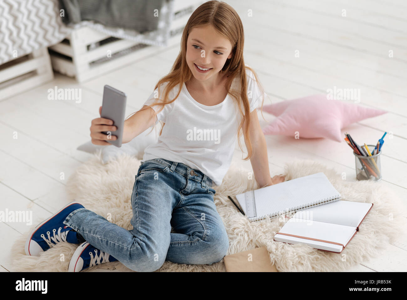 Radiant girl taking self portraits while doing homework Stock Photo - Alamy
