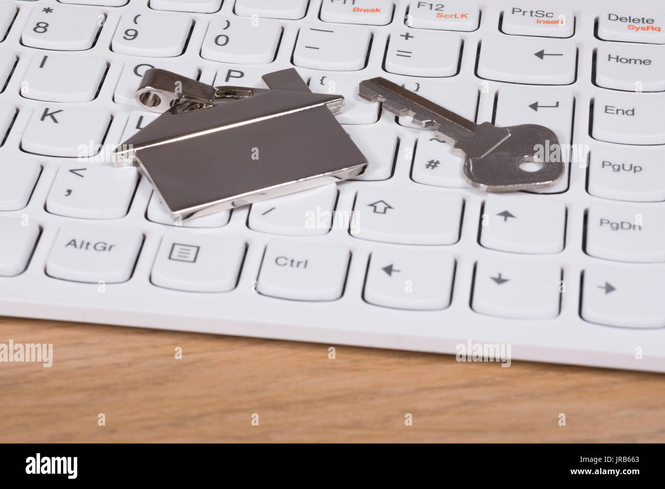 Metal pendant in shape of house with key lying on computer keyboard ...