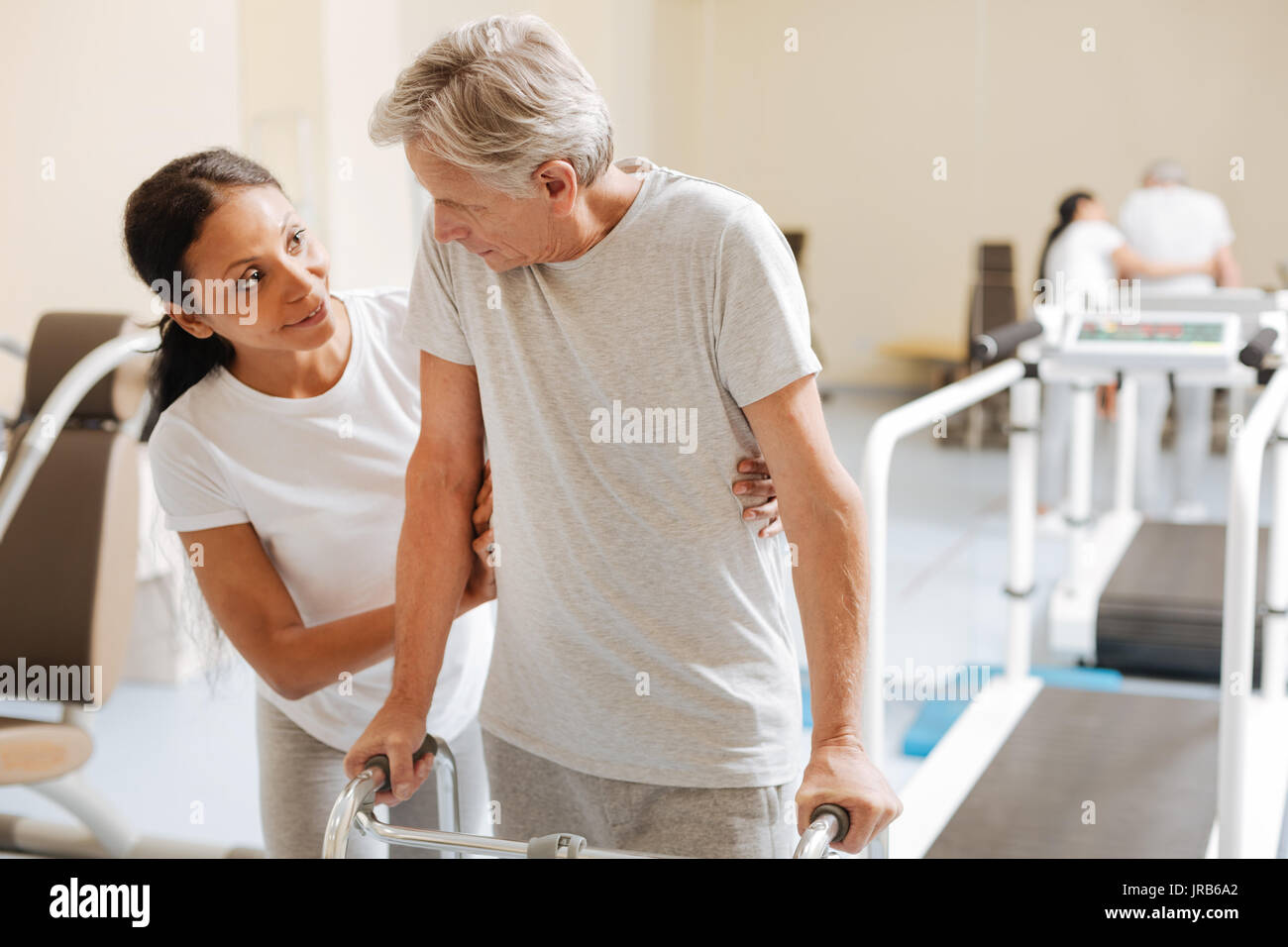 Friendly coach helping her patient in gym Stock Photo - Alamy