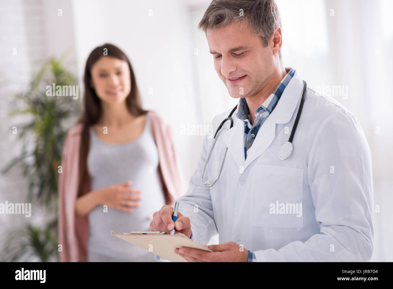 Positive medical worker looking at his notes Stock Photo - Alamy
