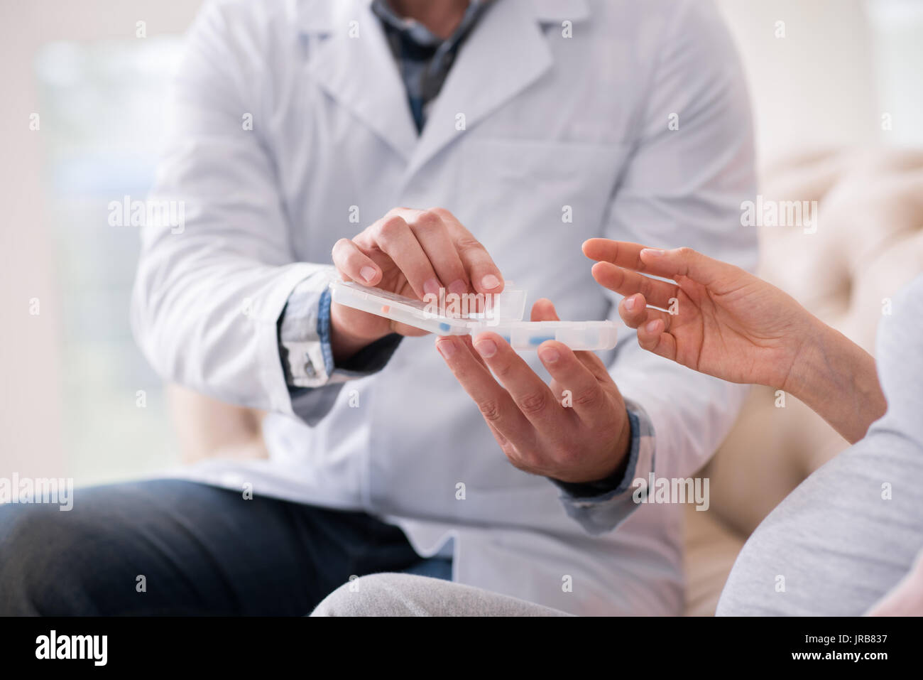 Professional doctor showing how to use container Stock Photo - Alamy