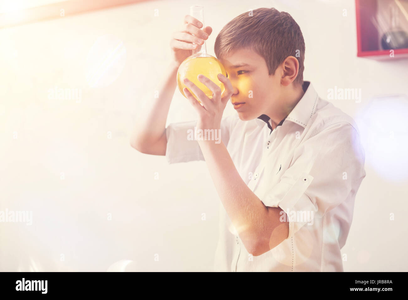 Serious boy holding bottle with yellow reagent Stock Photo - Alamy
