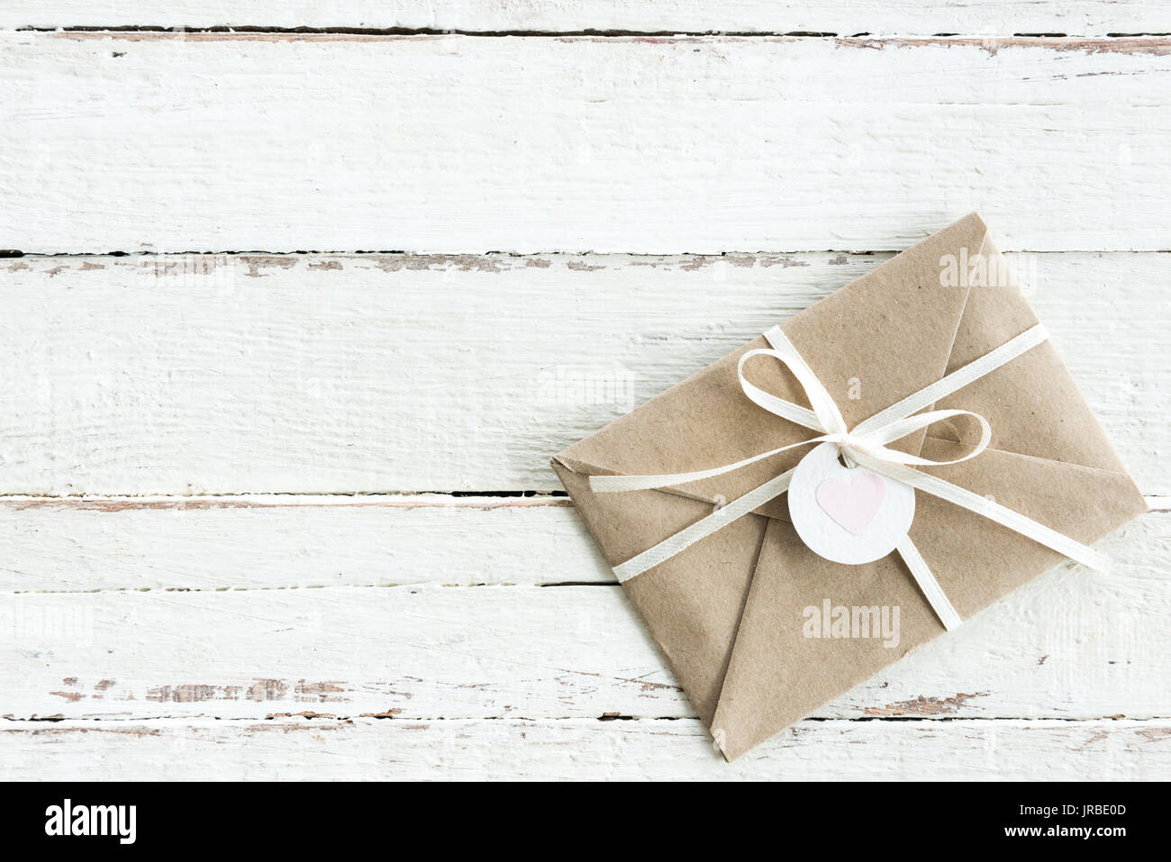 Top view of decorative kraft envelope with tag and ribbon on wooden ...