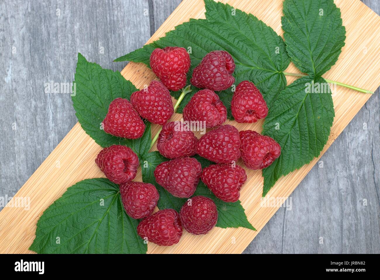 Fresh raspberries on a cutting board and a white wooden table Stock ...