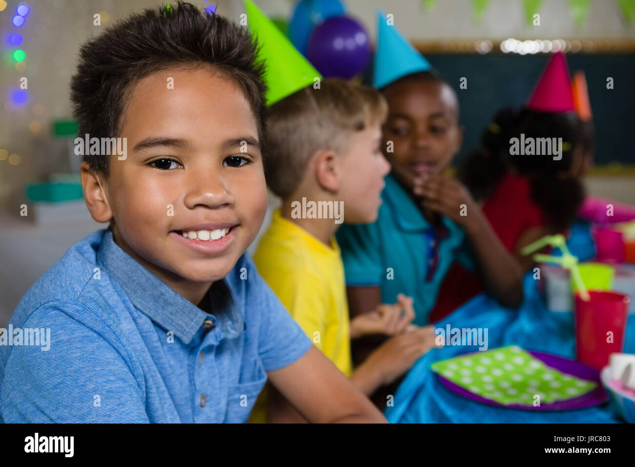 Portrait of boy sitting with friends during birthday party Stock Photo ...