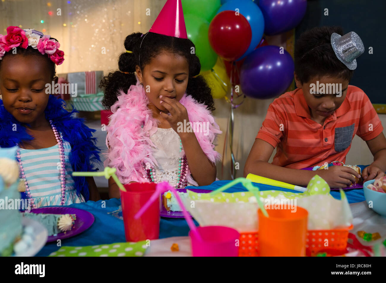 Kids having cake while sitting at table during birthday party Stock ...
