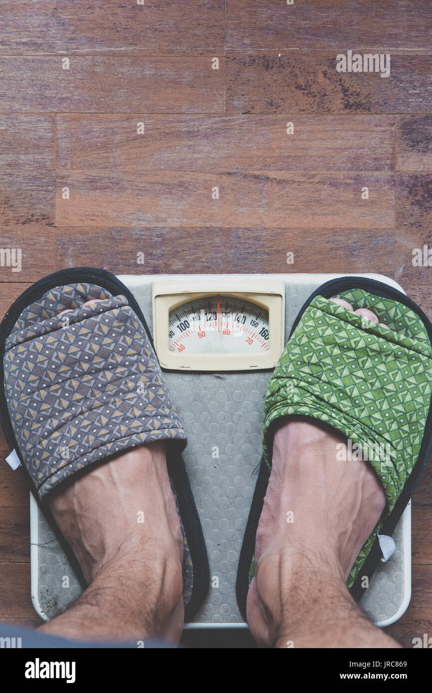 Man standing on weight scale Stock Photo - Alamy