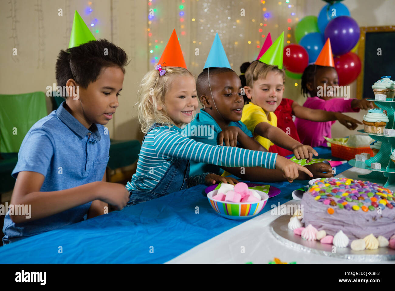 Kids pointing on cake at table during birthday party Stock Photo - Alamy