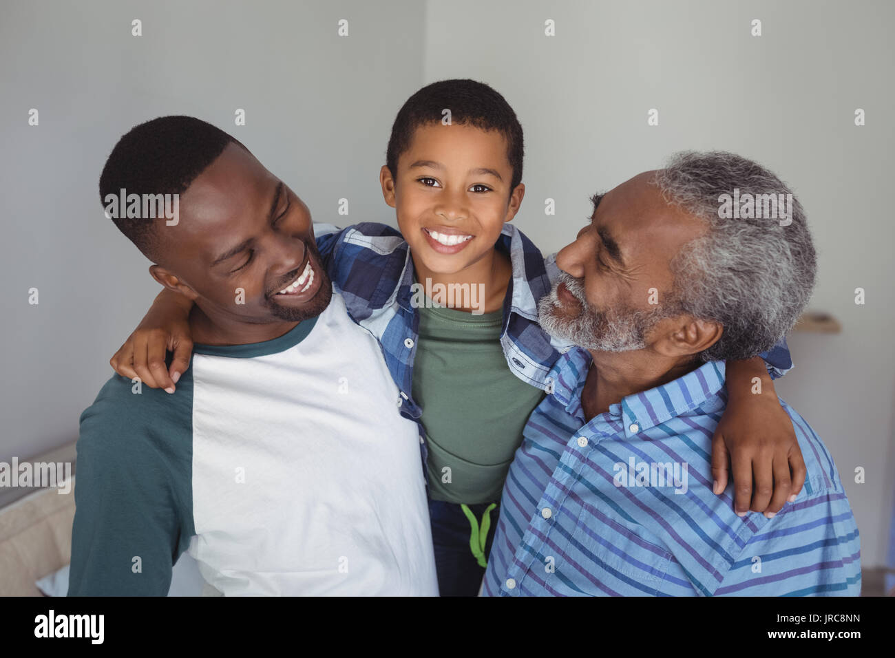 Smiling multi-generation family standing together in bedroom at home ...