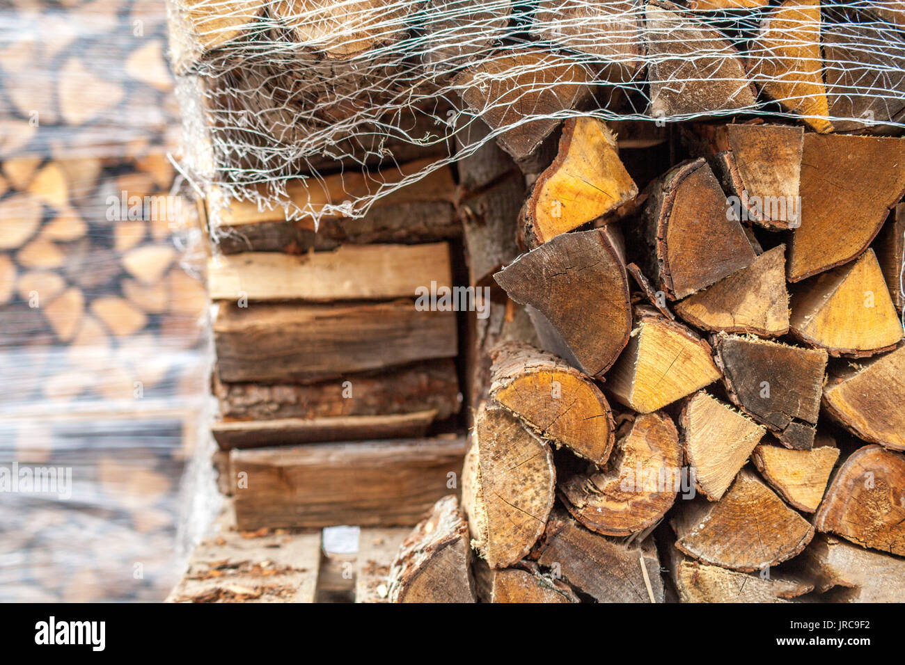 split logs in a logpile wrapped in netting Stock Photo - Alamy