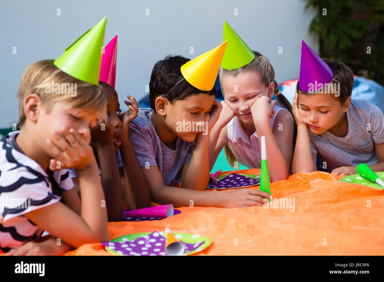 Bored children with hand on chin sitting at table during birthday party ...