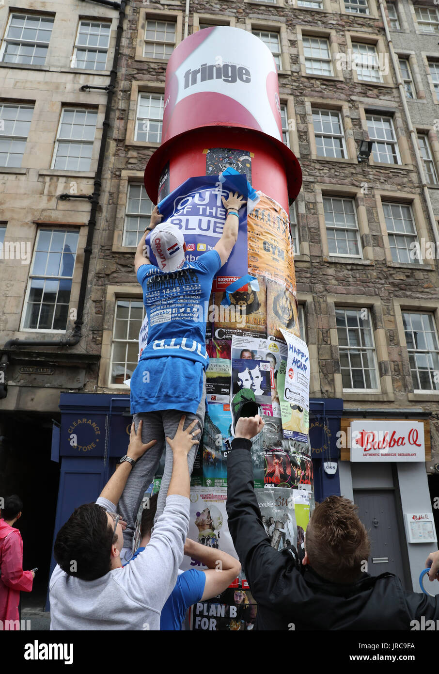 A performer puts up a poster advertising a Fringe show on the Royal ...