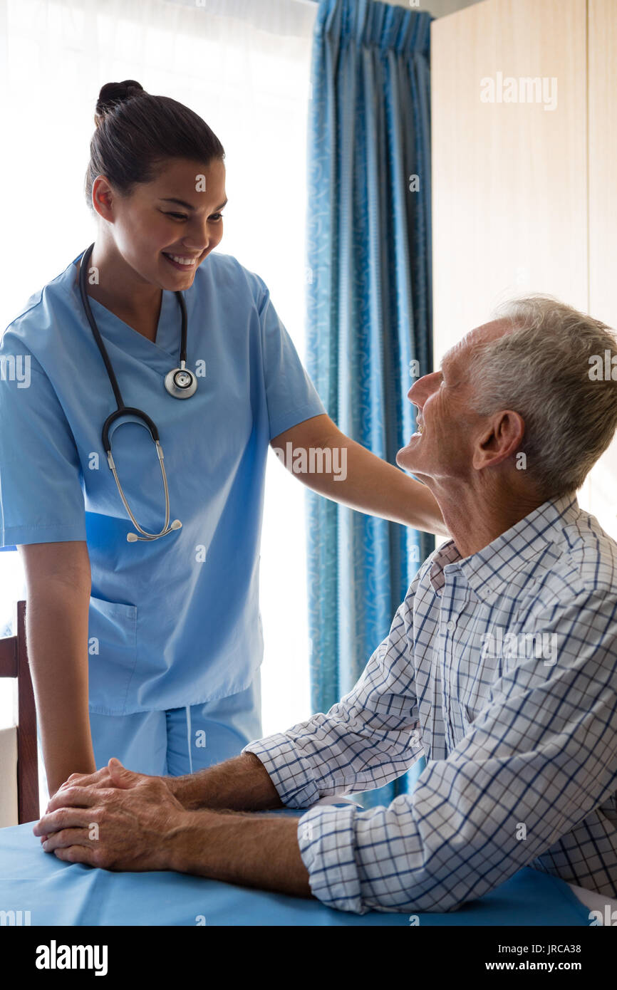 Smiling female doctor consoling senior man in retirement home Stock ...