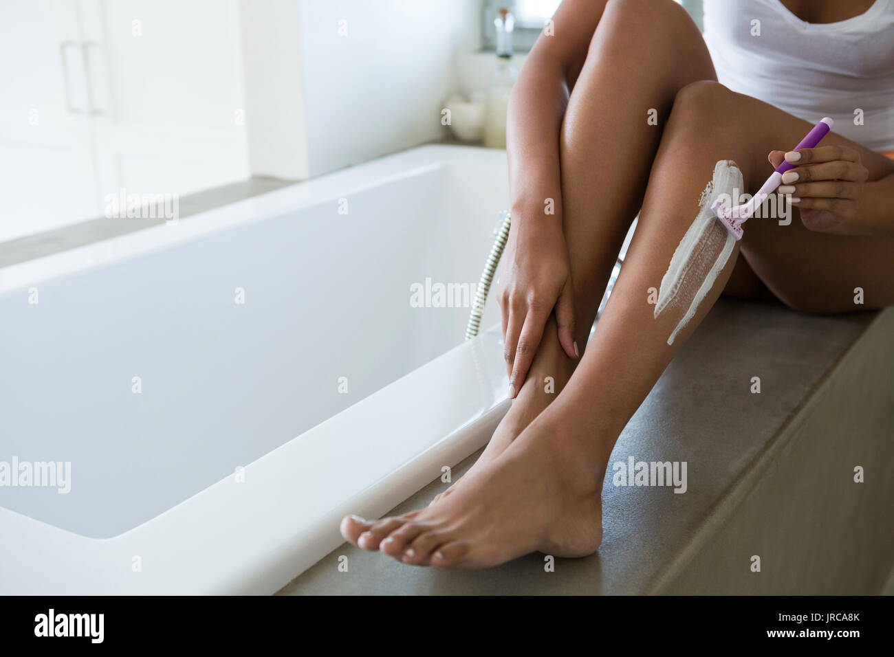 Low section of young woman shaving leg in bathroom Stock Photo - Alamy
