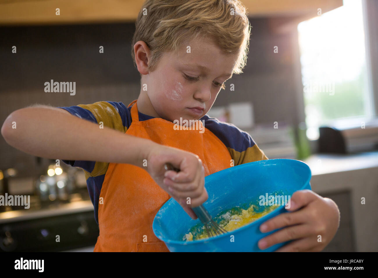 Boy mixing batter in blue container at kitchen Stock Photo - Alamy