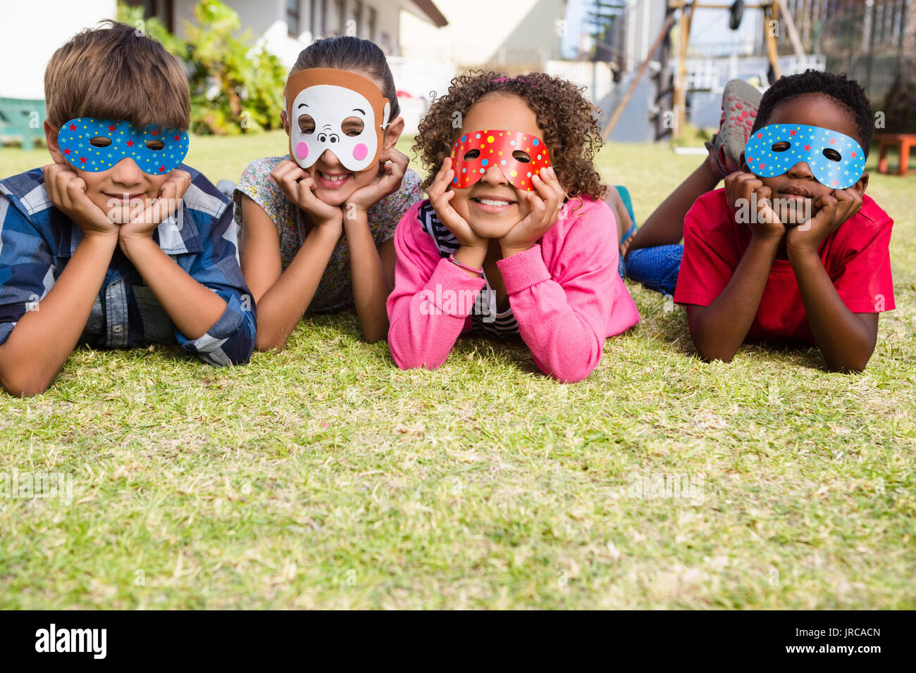 Children wearing masks lying on field in yard during sunny day Stock ...