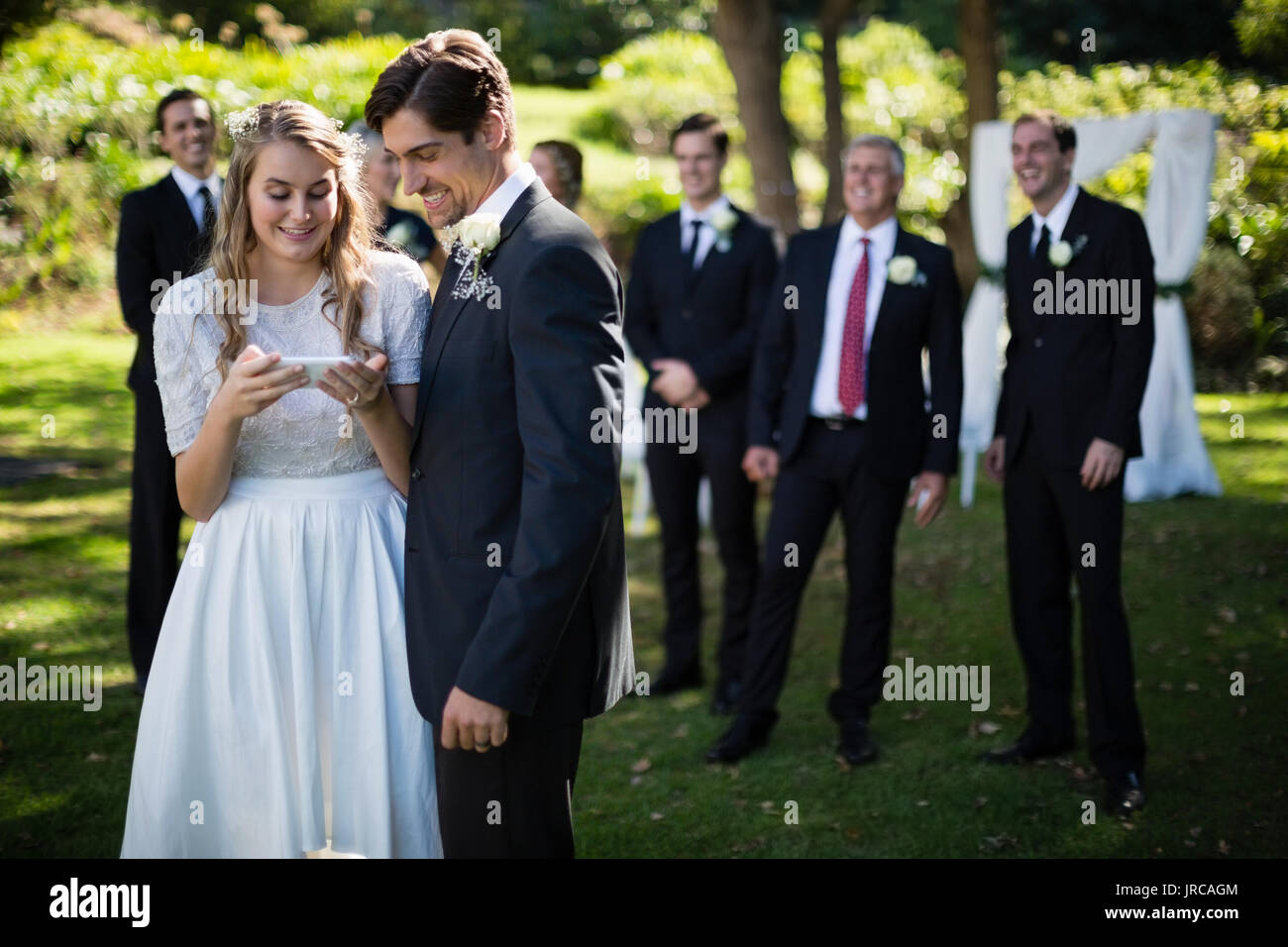Bride and groom reviewing photographs on mobile phone during wedding ...