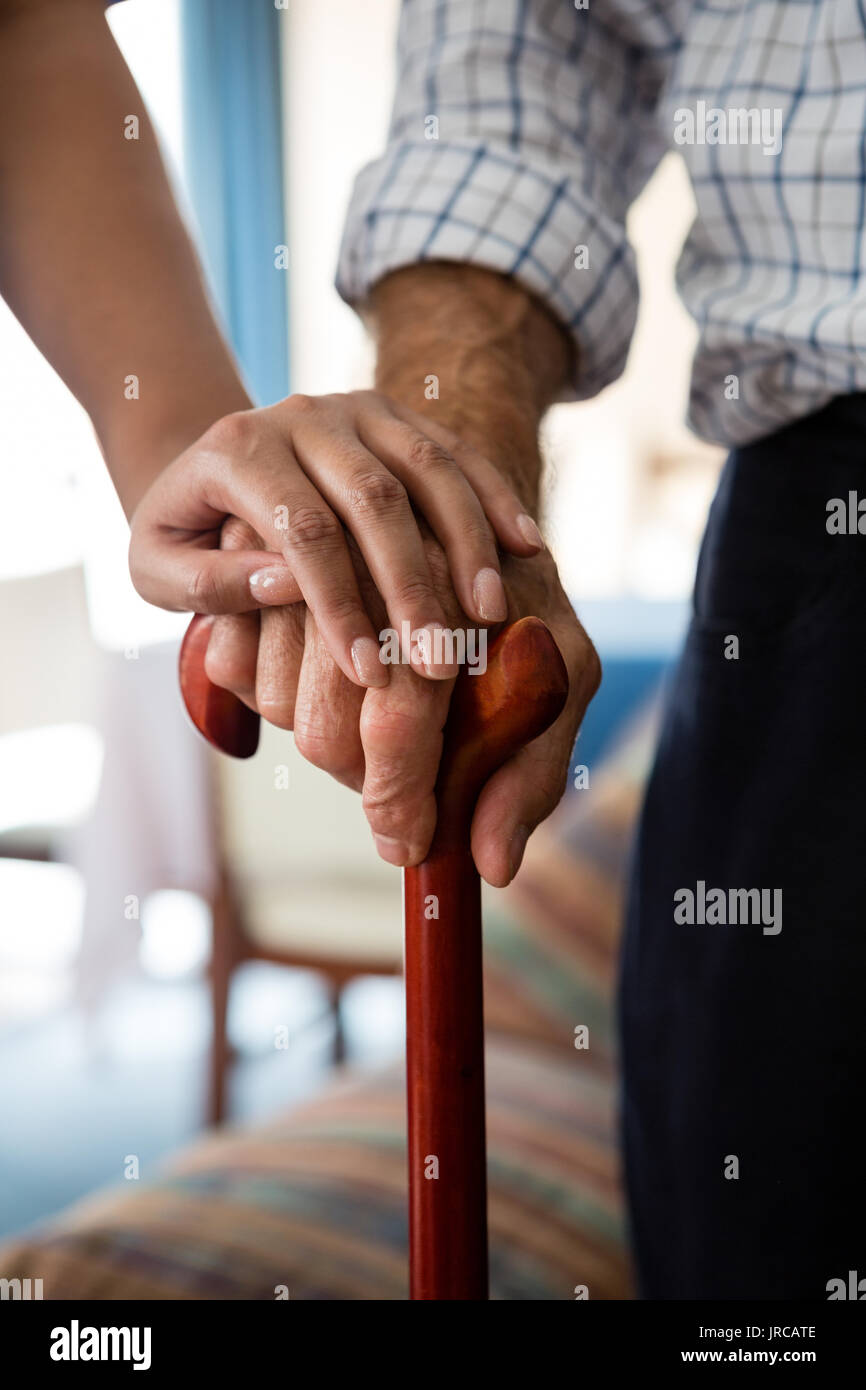 Cropped hands of female doctor and senior man holding walking cane in ...