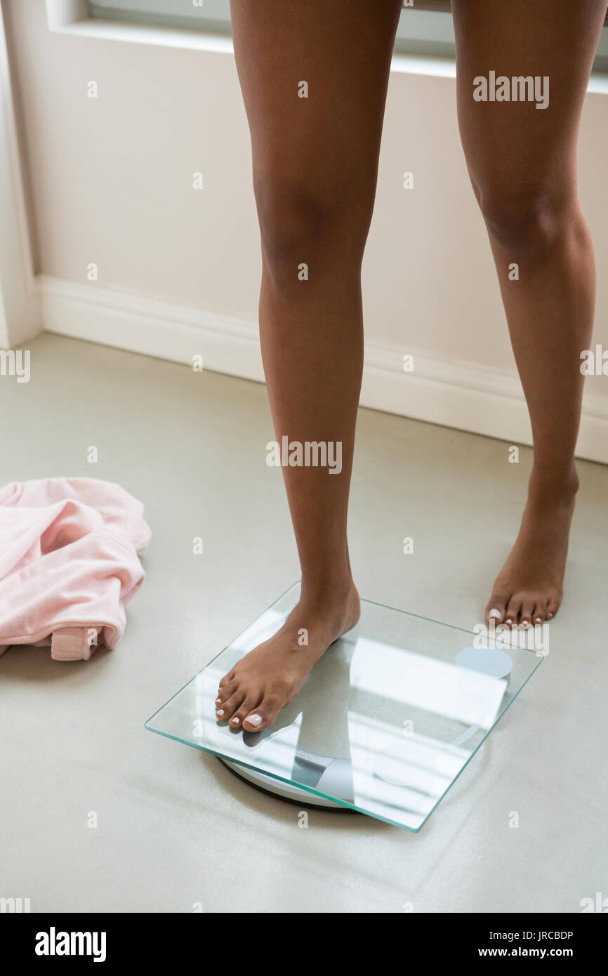 Low section of woman standing on weight scale in bathroom at home Stock ...