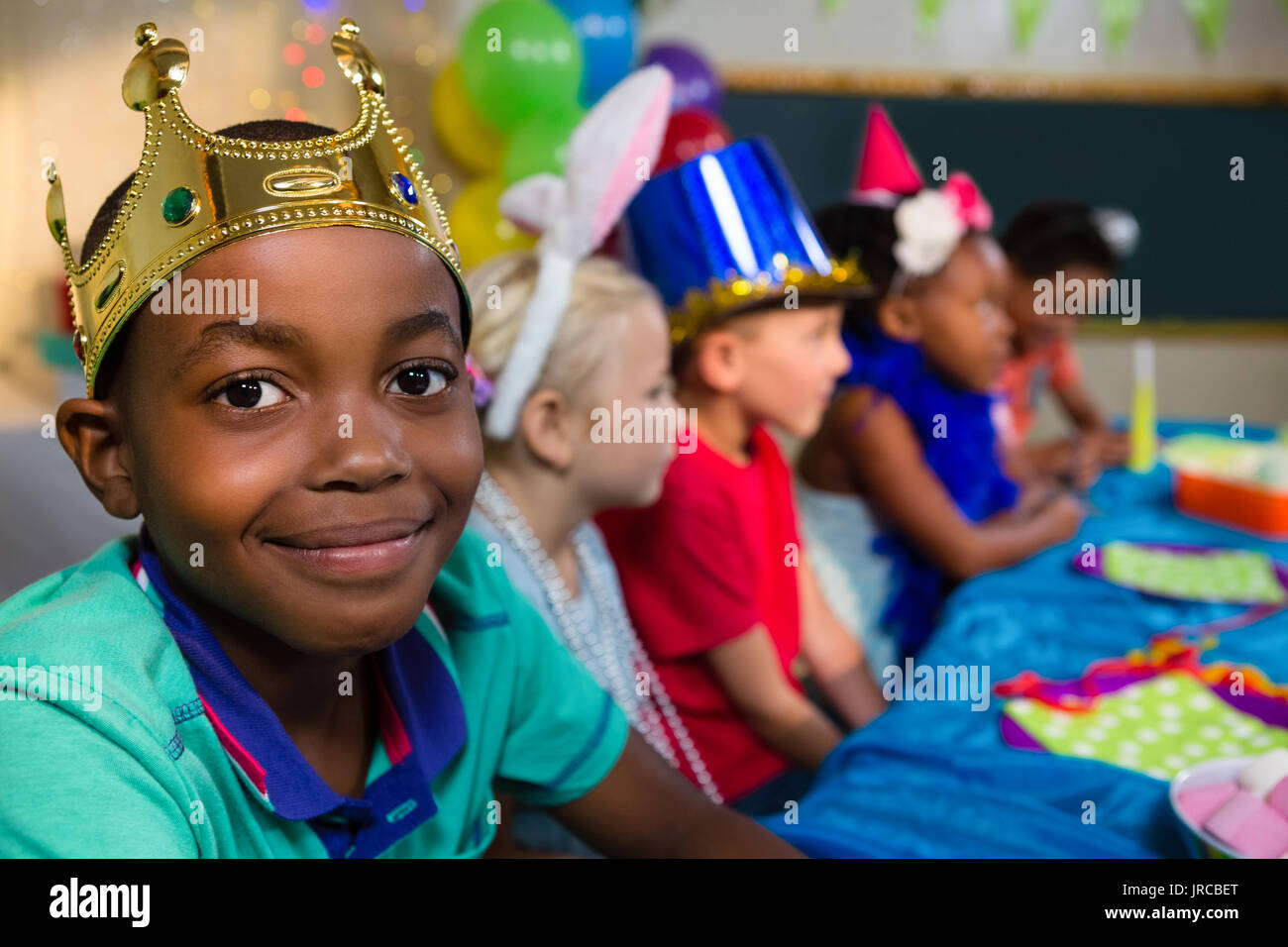 Portrait of smiling boy wearing crown with friends in background during ...