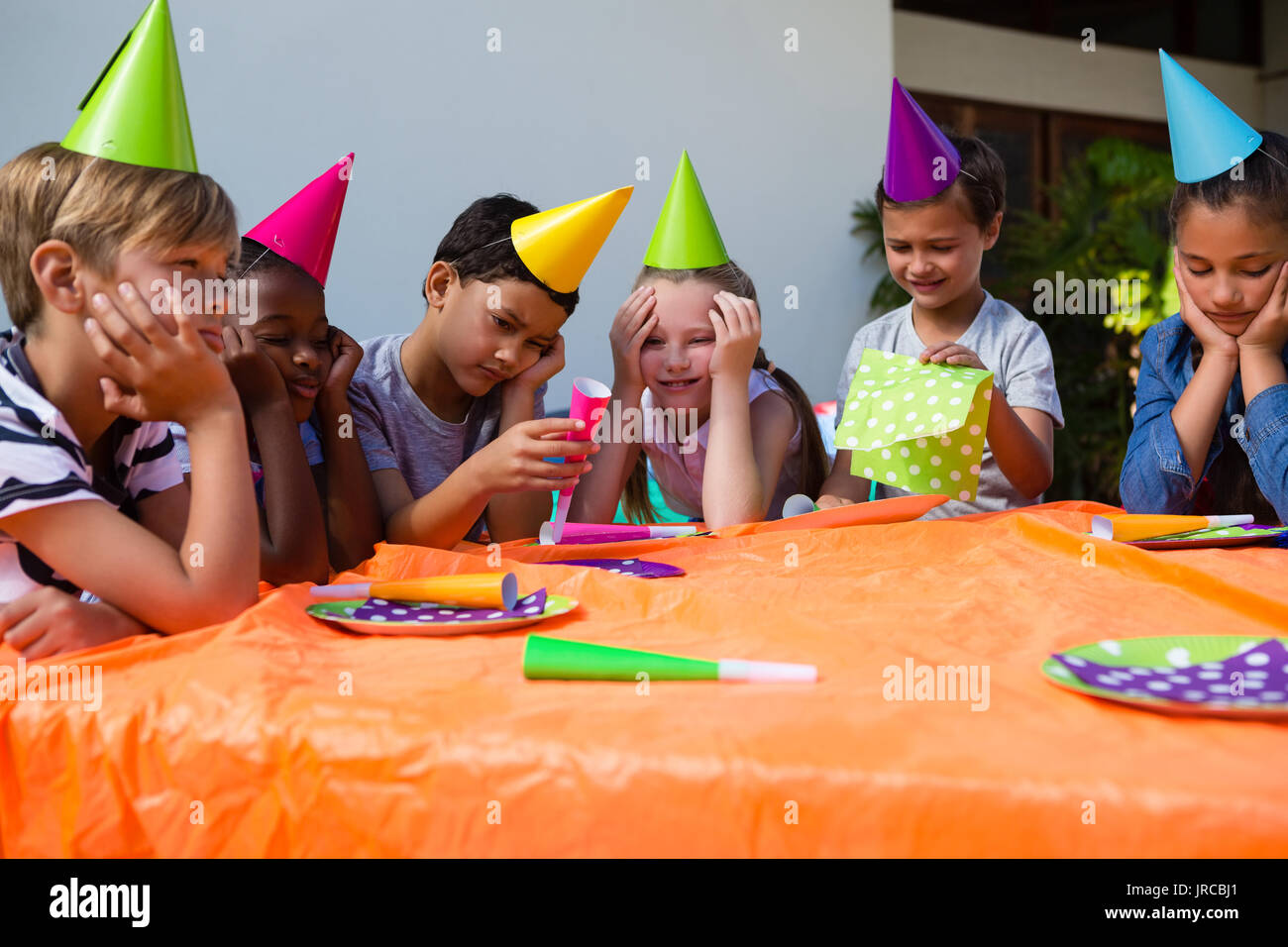 Bored children sittng at table in yard during birthday party Stock ...