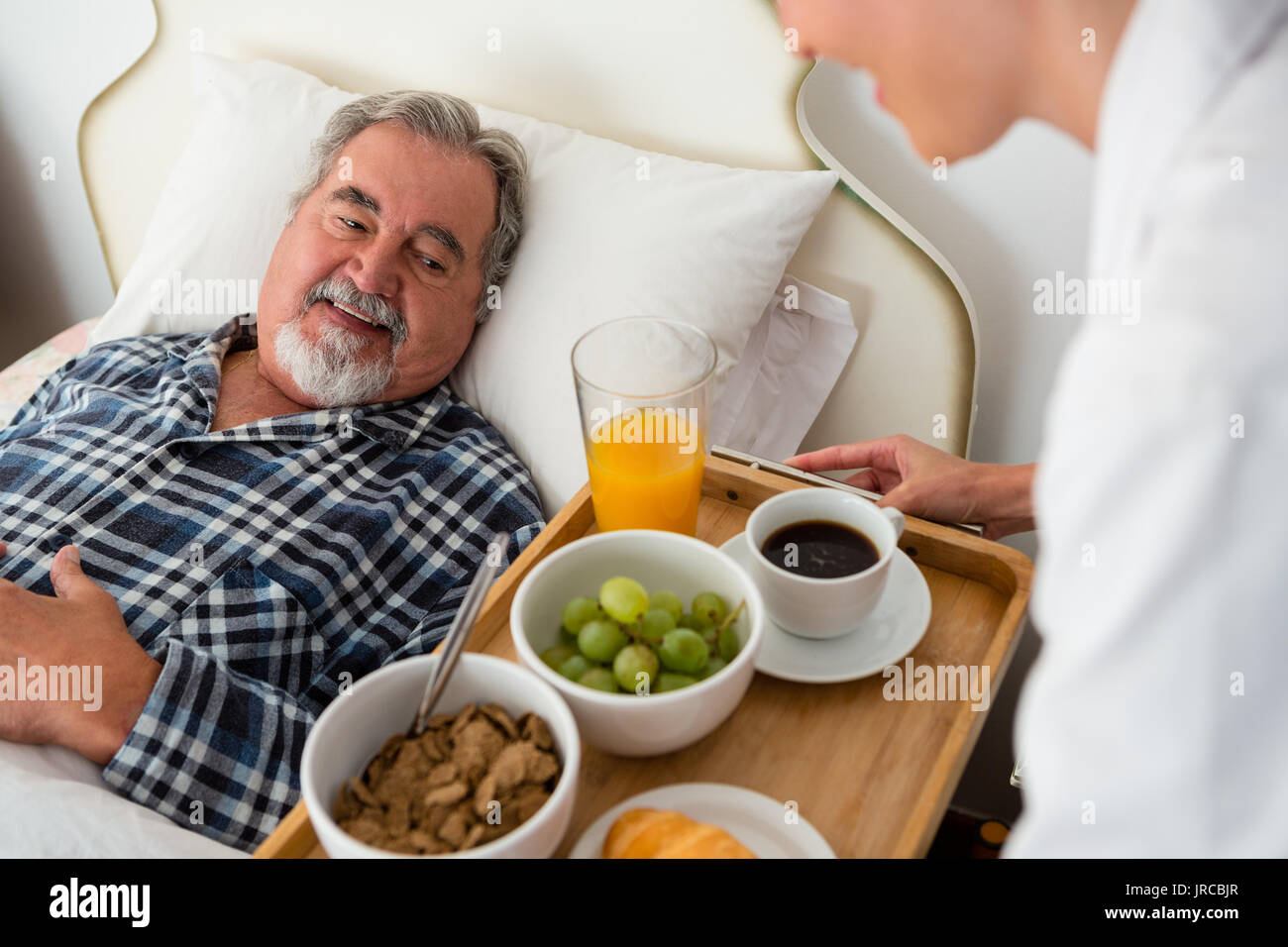 Cropped hand of female doctor serving food to senior patient relaxing ...