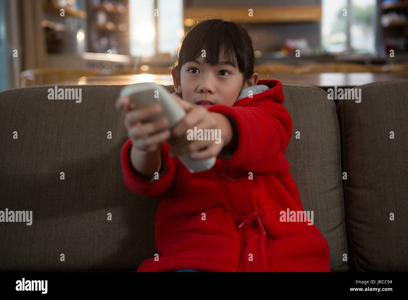 Girl using remote control while relaxing on sofa at home Stock Photo ...