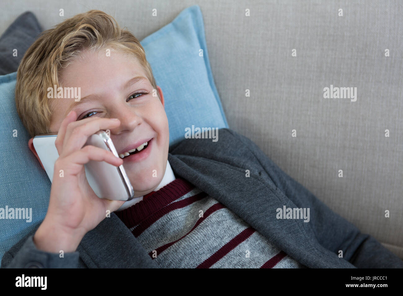 Little boy playing with phone on couch Stock Photo - Alamy