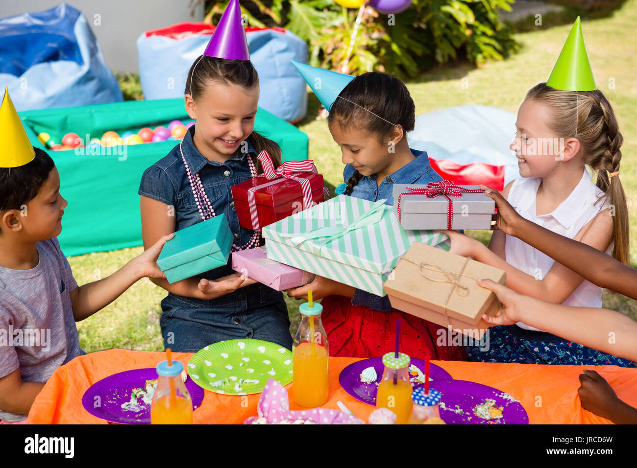 Cheerful girl receiving gifts from friends during birthday Stock Photo ...